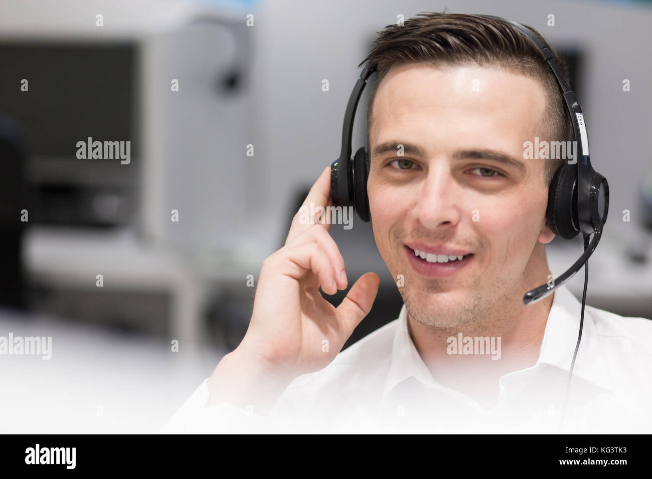 young smiling male call centre operator doing his job with a headset Stock Photo - Alamy