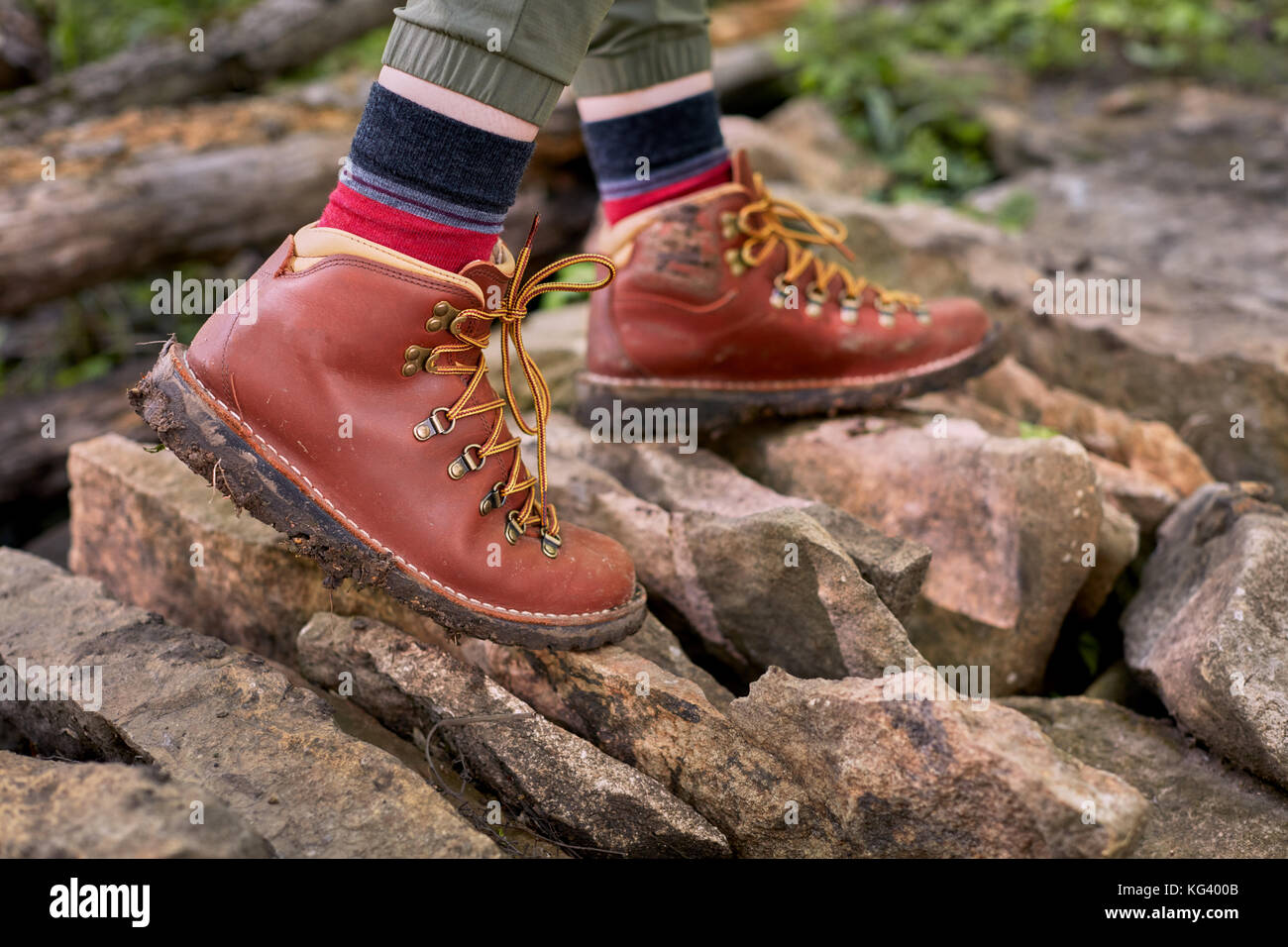 Side view of hiker in brown boots and socks walking over rocks outdoors ...