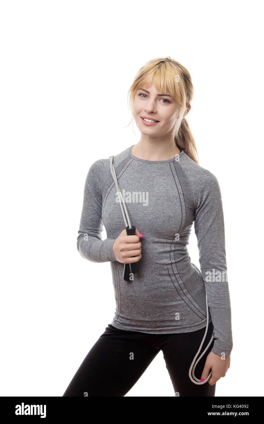 standing fitness woman in a grey top with a skipping rope around her ...