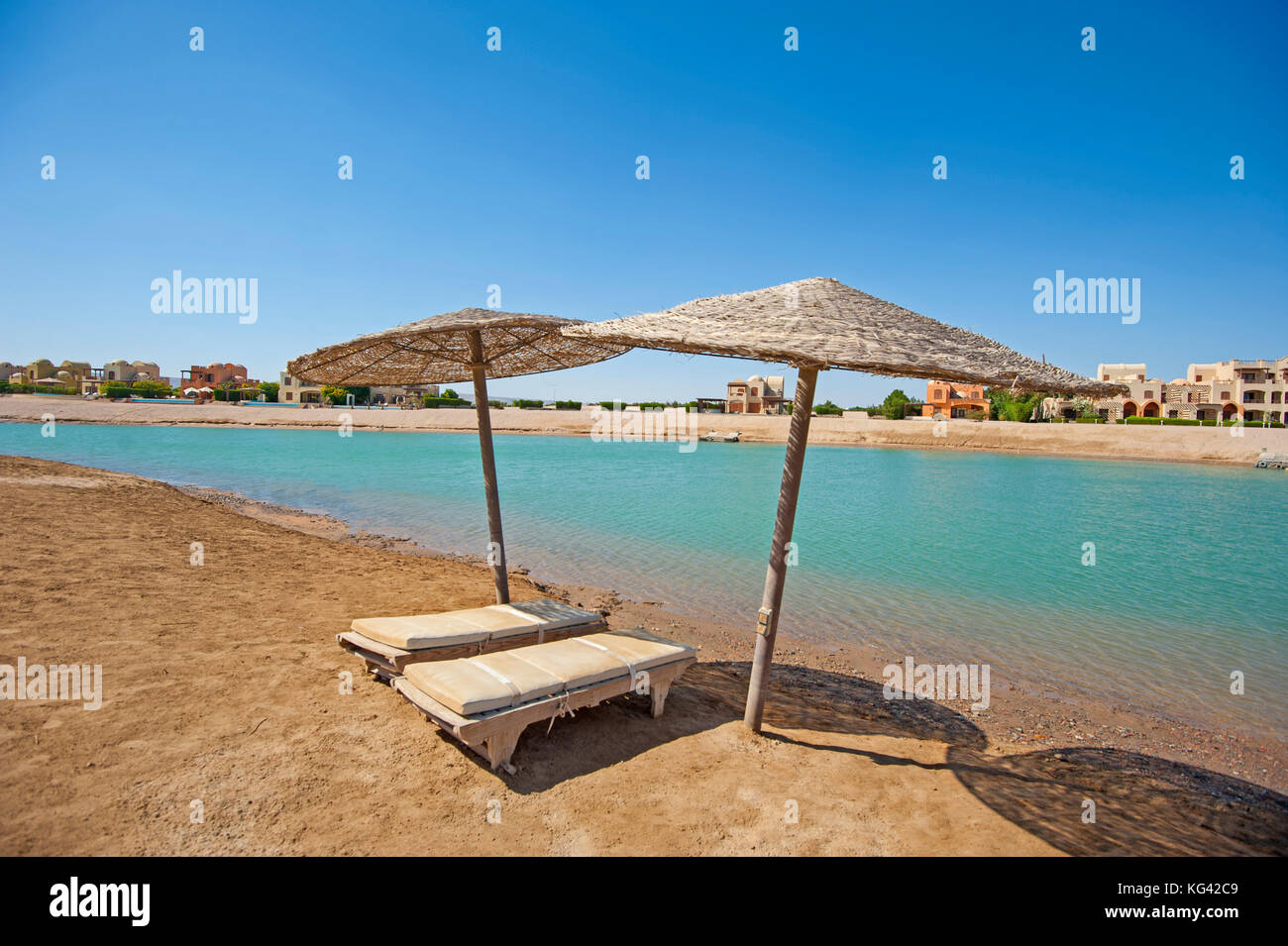 Pair of sun lounger beds on remote tourist resort tropical sandy beach ...