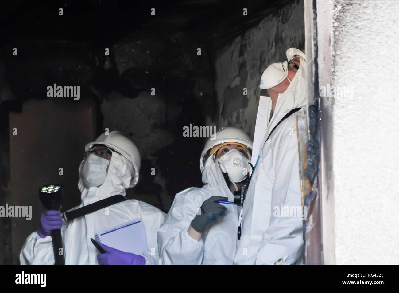 Fire investigation officers examine the scene of a fatal house fire to ...