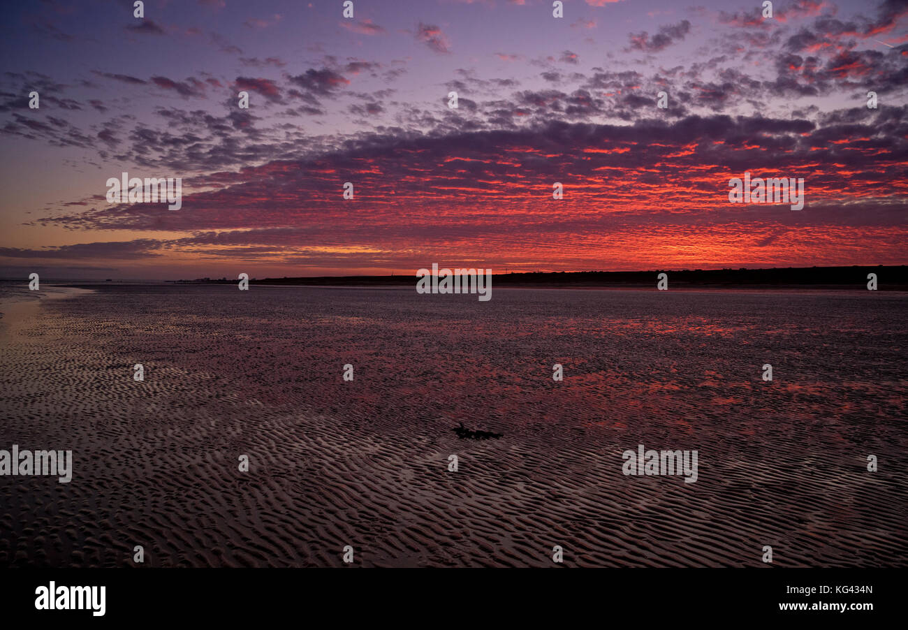 Dramatic fiery red sunset sky reflecting in the pools of water in the ...