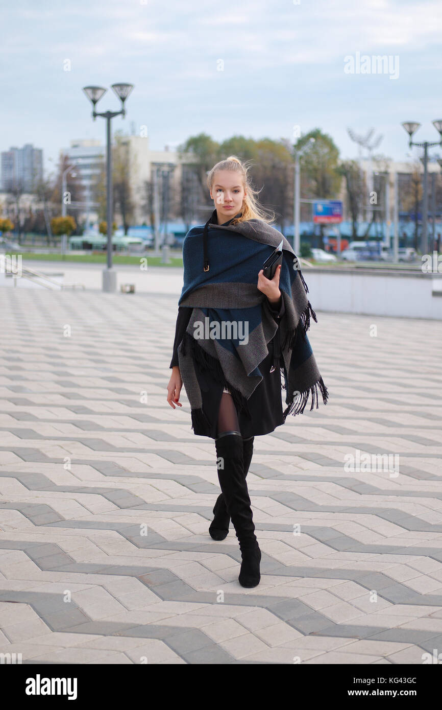 Pretty girl in warm wool coat and scarf wrapped around neck walking on ...