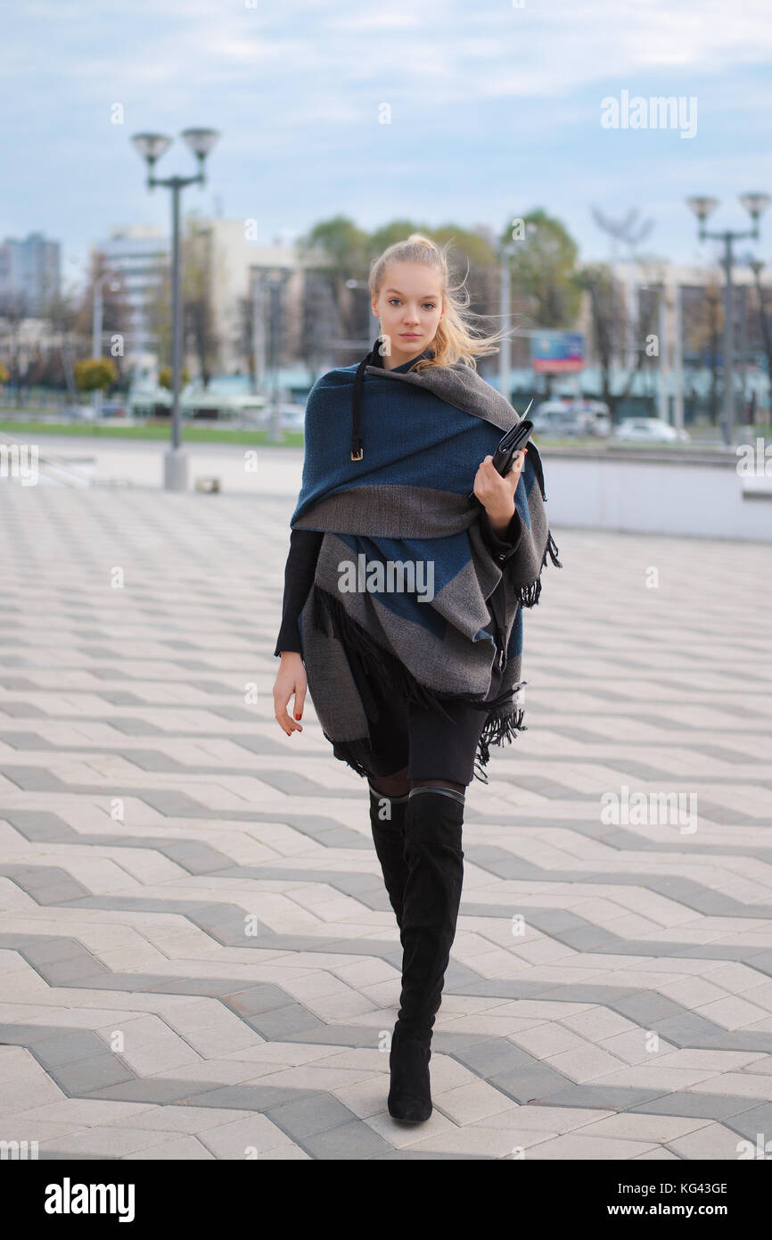 Pretty girl in warm wool coat and scarf wrapped around neck walking on ...