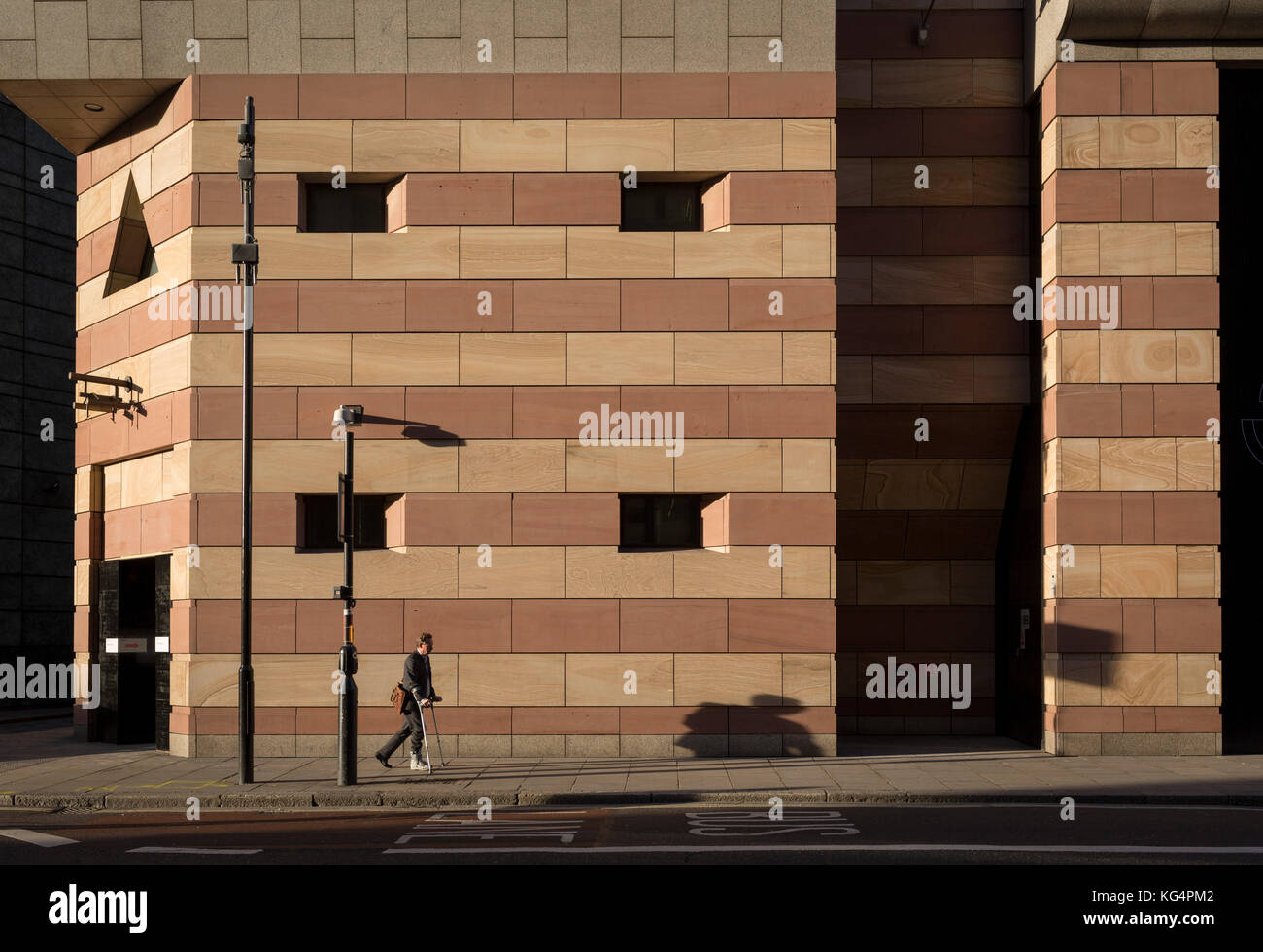 A man hobbles on crutches beneath the modern architecture of One ...