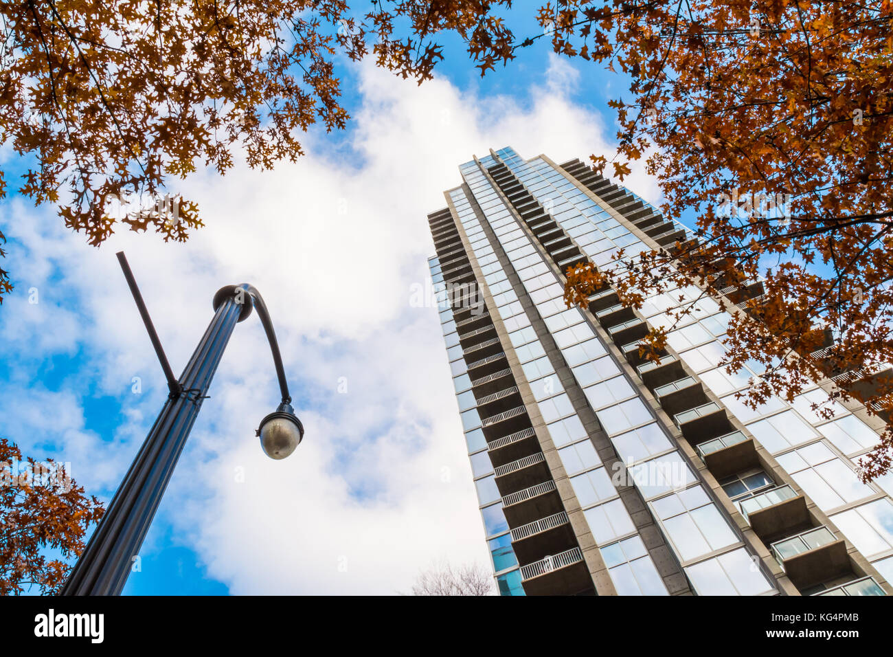 Bottom view of streetlight and skyscraper on the background of cloudy ...