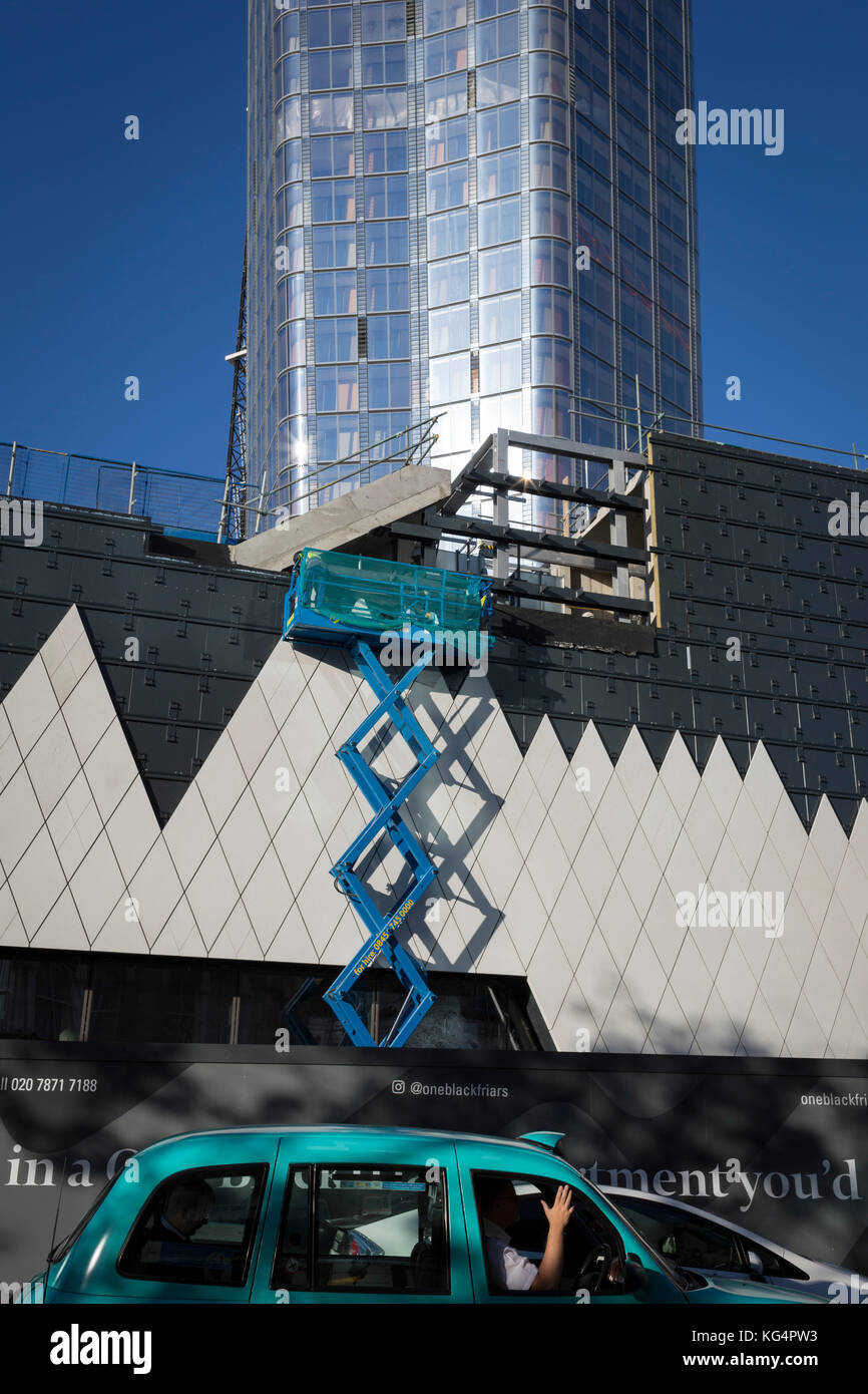 Workmen fix triangular-shaped cladding to the exterior of a part of the ...