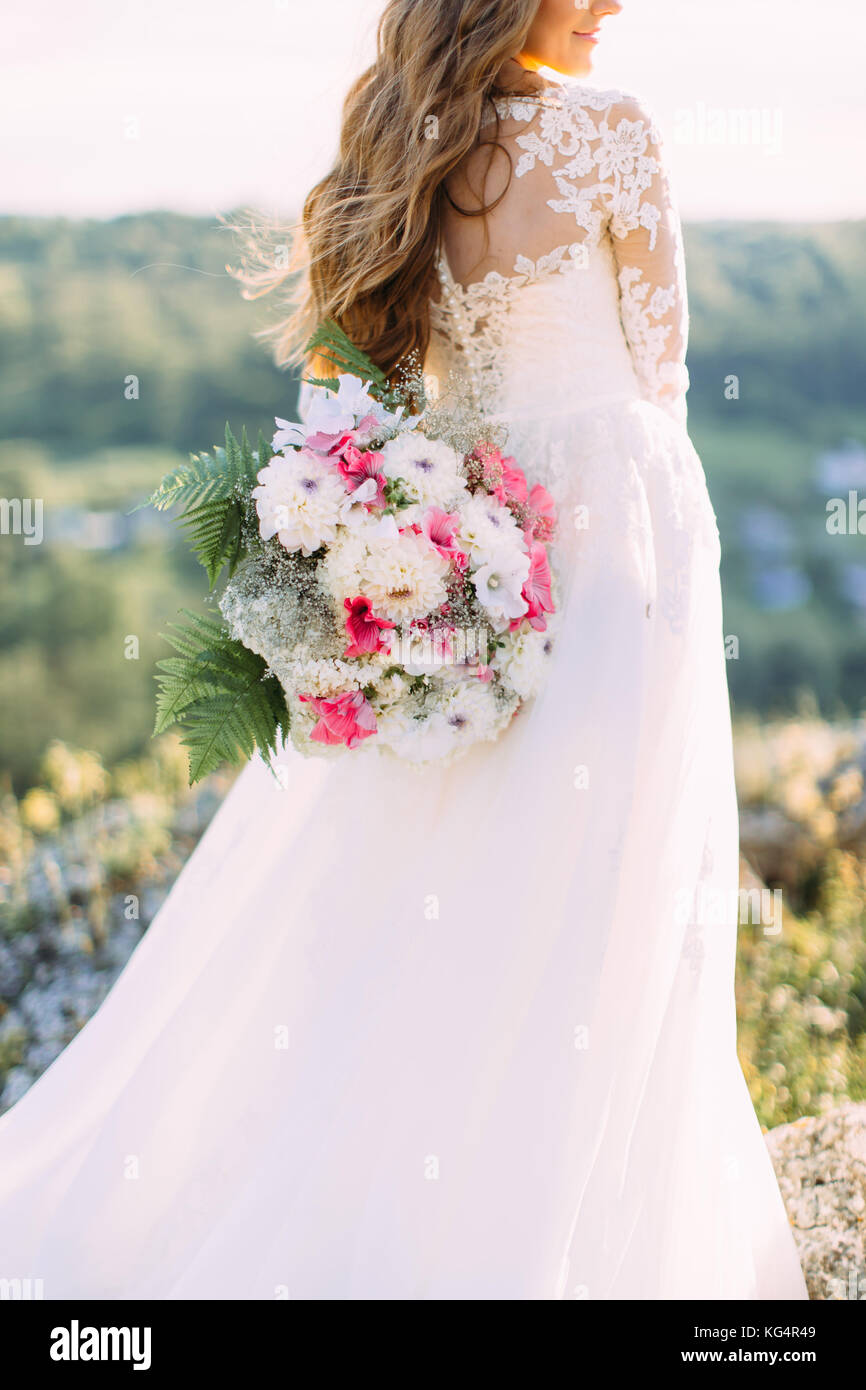 The close-up vertical portrait of the back of bride dressed in the long ...
