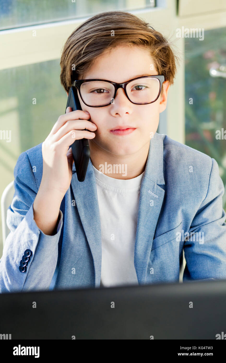 Portrait of teen boy talking over mobile phone and using laptop Stock ...