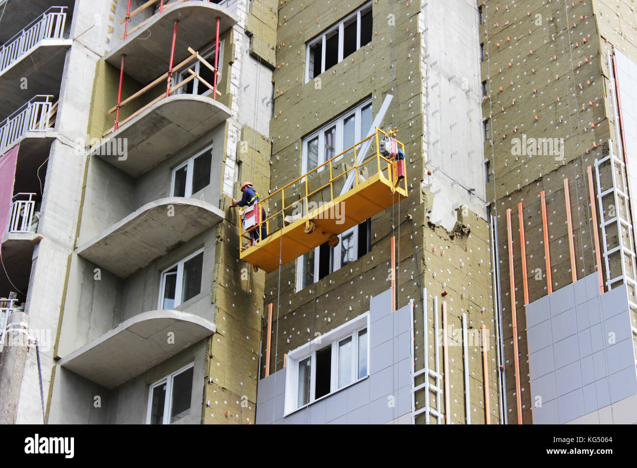 worker in yellow front suspended cradle on a newly built high-rise ...
