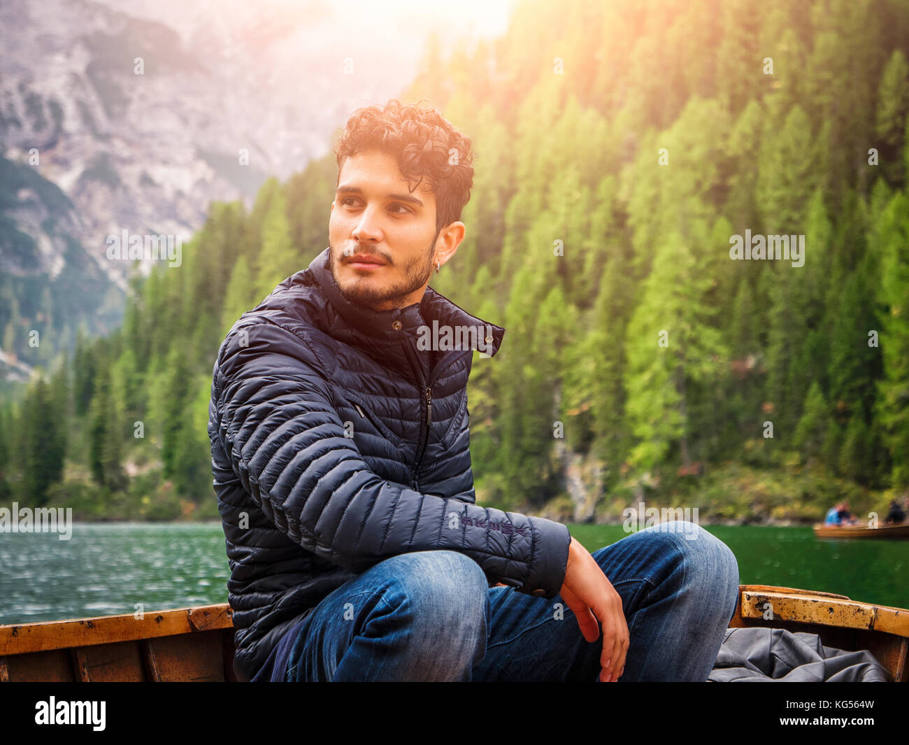 Young casual man sitting in boat and rowing while looking away on ...