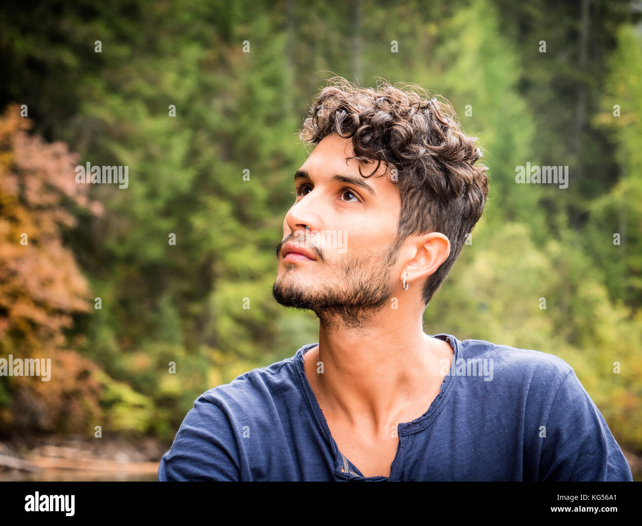 Handsome yung man standing on background of woods looking away Stock ...