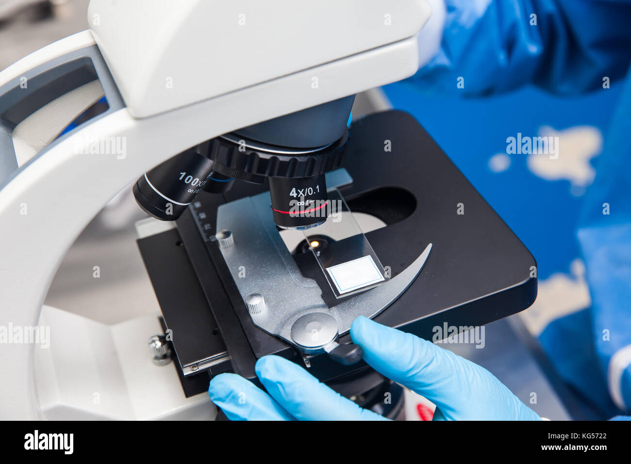 Young male scientist looking at slides under the microscope Stock Photo ...