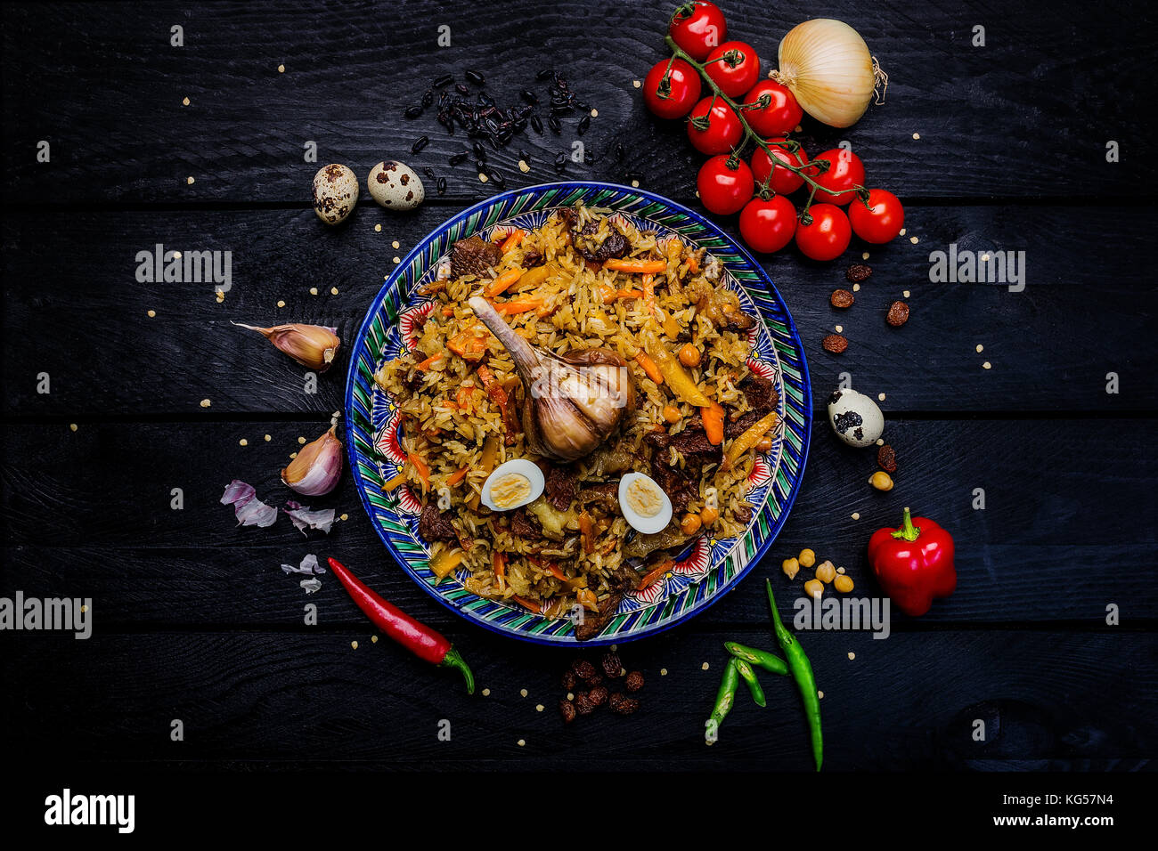 Pilaf and ingredients on plate with oriental ornament on a dark wooden ...