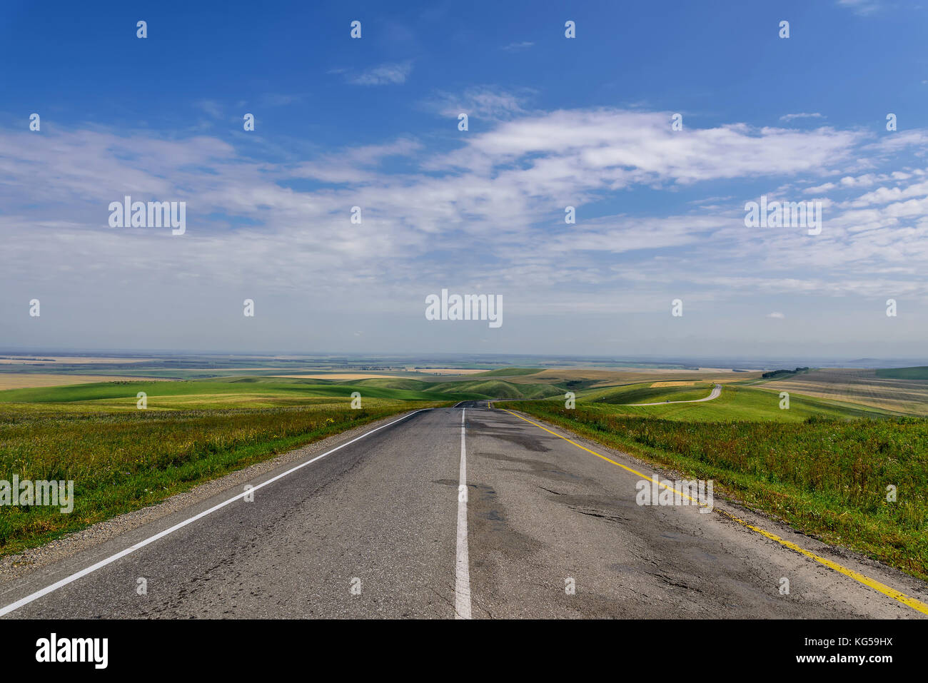 A picturesque rural view with an asphalt road through the hills amidst ...