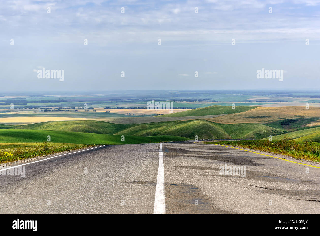 A picturesque rural view with an asphalt road through the hills amidst ...
