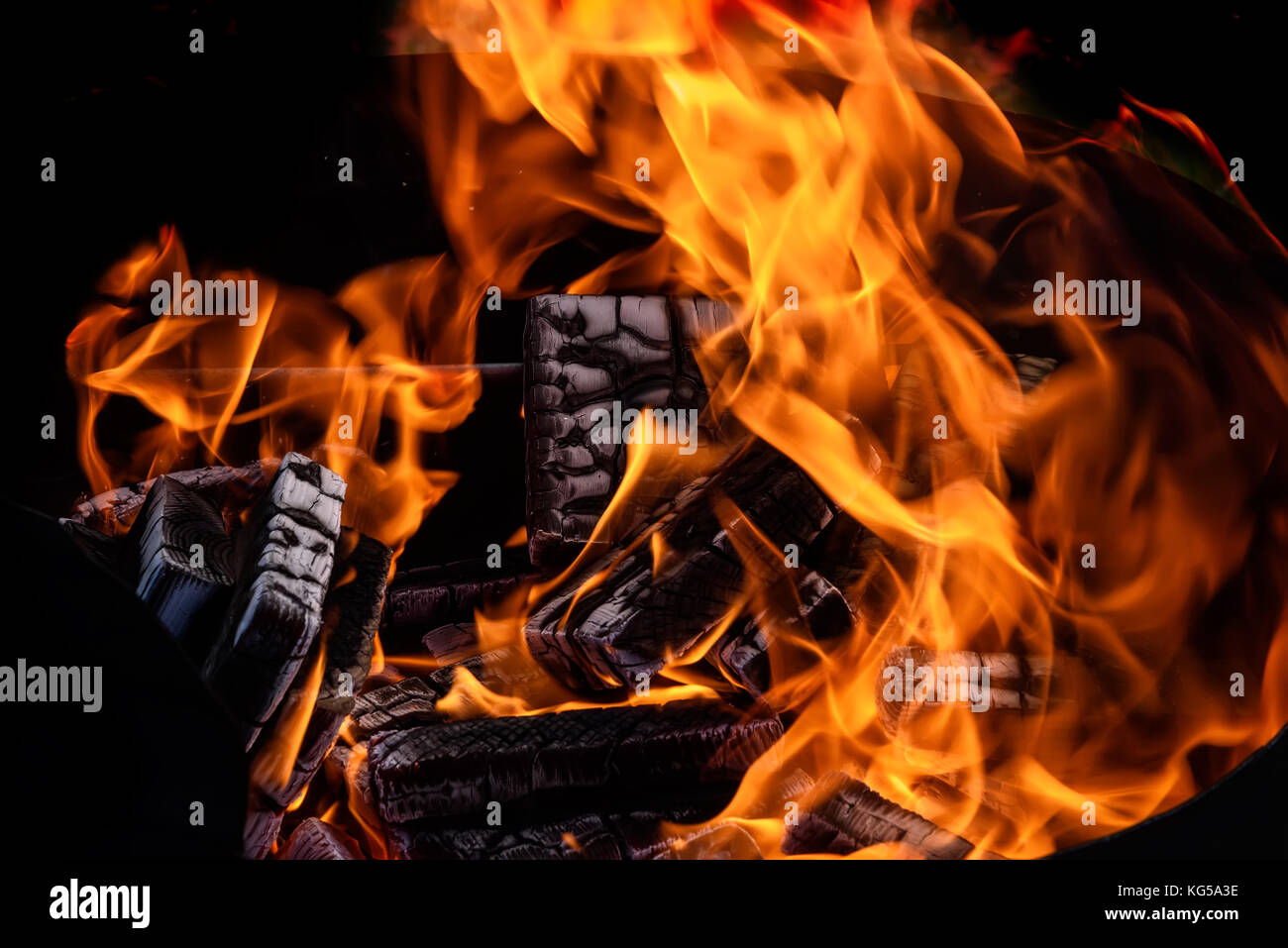 Red and orange flame of a bonfire and black pressed coal in brazier for ...