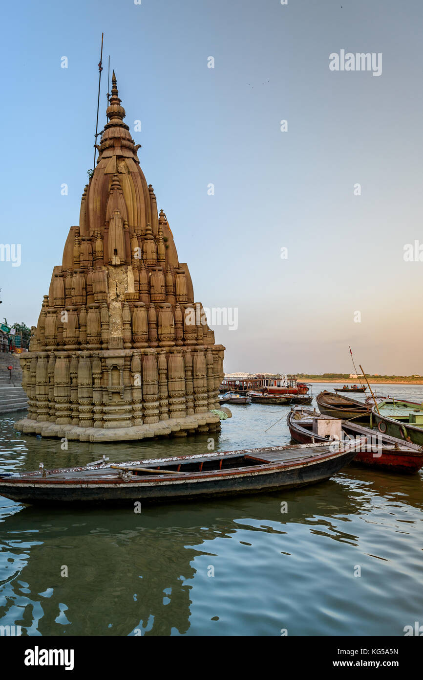 An ancient submerged temple in water and wooden boats anchored near the ...