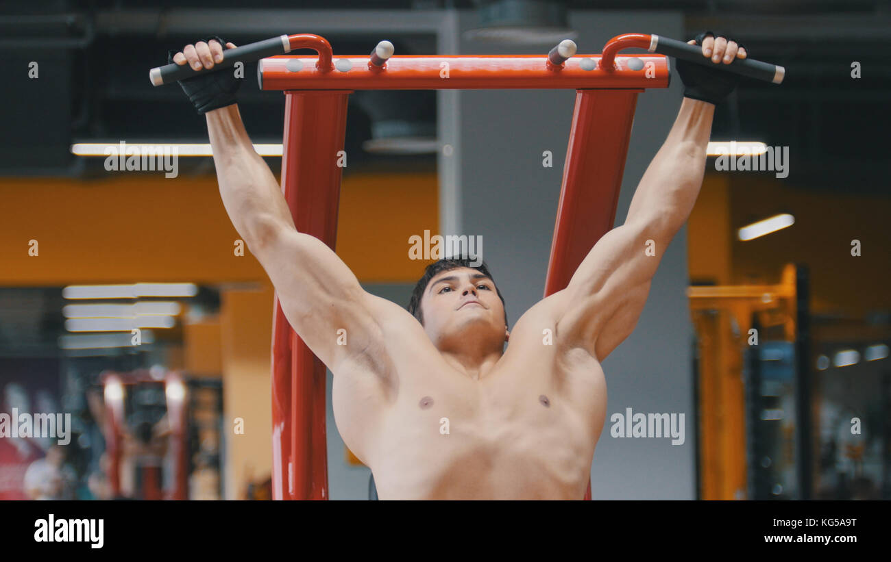 Muscular young man pulling up in a gym, close up Stock Photo - Alamy