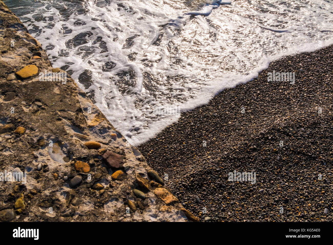 Textures of pebble beach, sea foam and concrete slab photographed ...