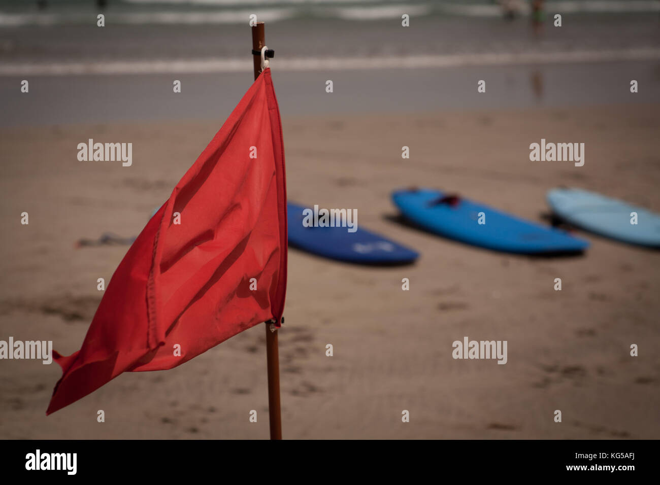 red flag flap on the beach, surfboards in background Stock Photo - Alamy