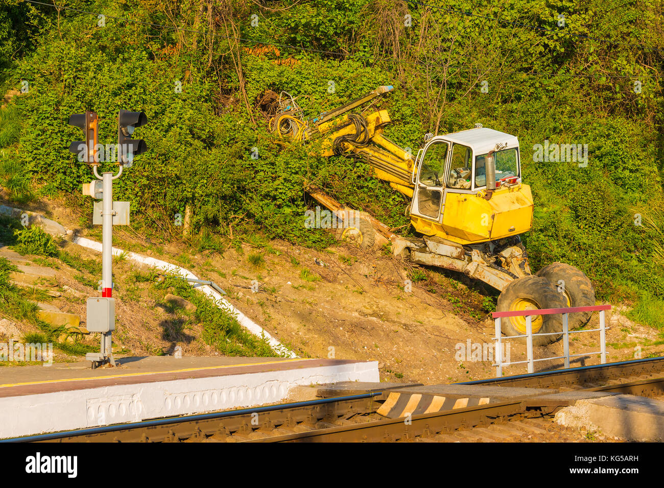 Abandoned old excavator overgrown with grass and bushes near railroad ...