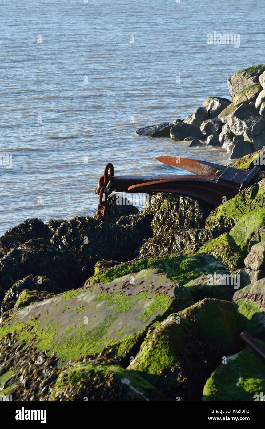 Rusty anchor on rocks Stock Photo - Alamy