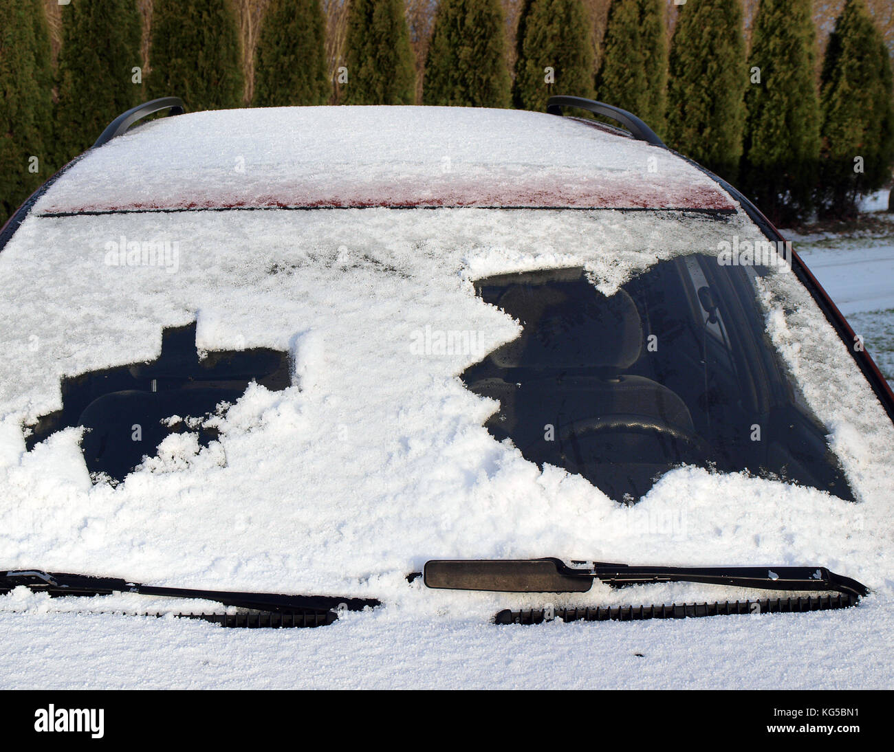 Snow covered car front window partly cleaned both sides, horizontal ...