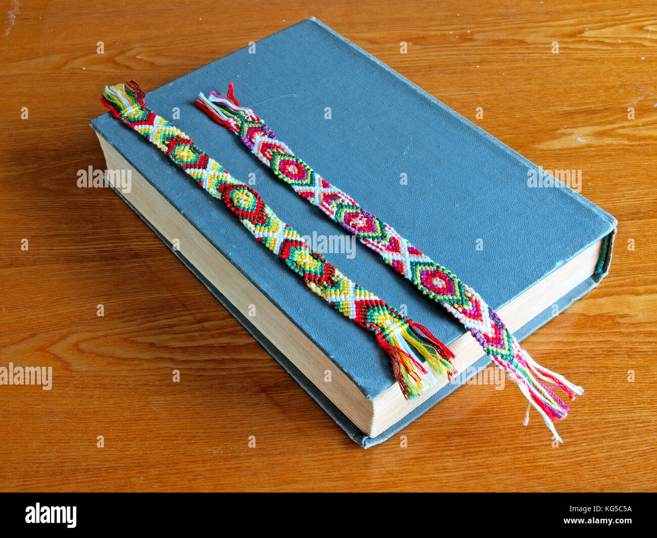 Colorful bookmarks braided from different threads on blue book wooden ...