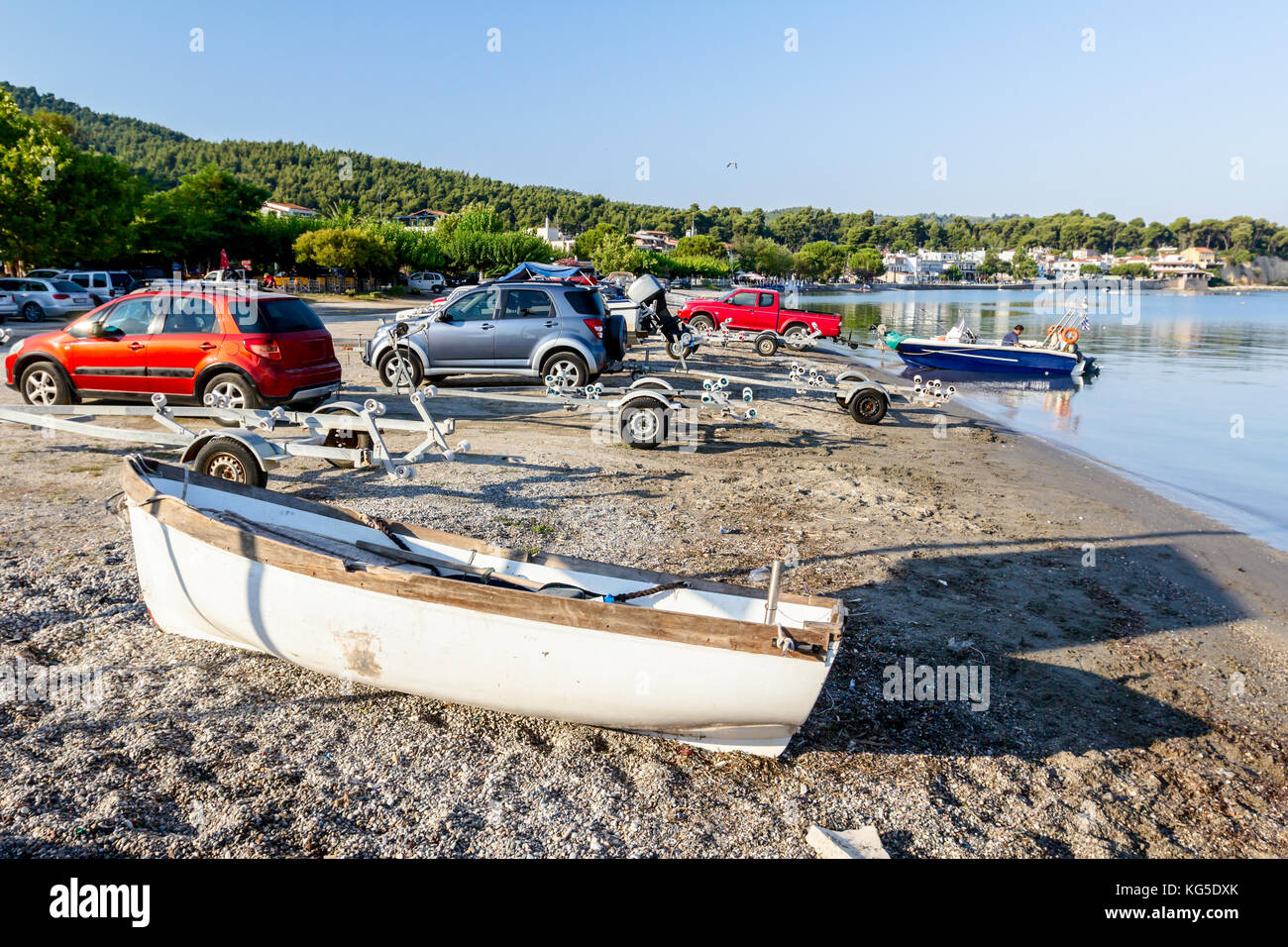 Several cars are parked on the beach with trailers for transport boats ...