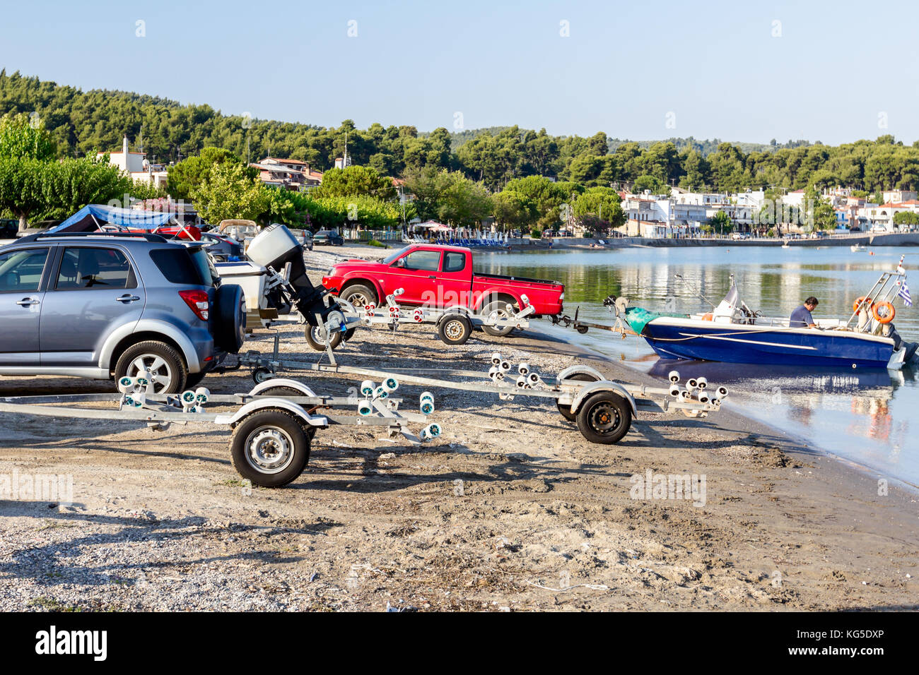 Several cars are parked on the beach with trailers for transport boats ...