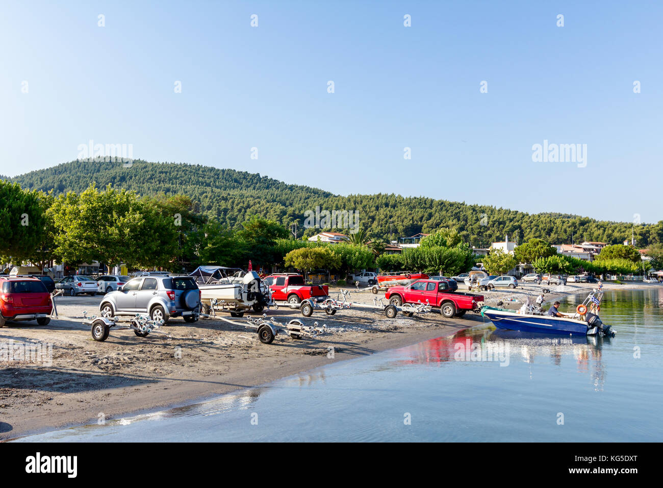 Several cars are parked on the beach with trailers for transport boats ...