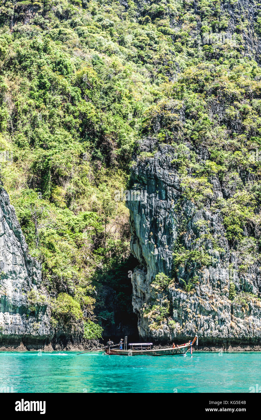 A fisherman's boat at the bottom of a shear cliff face rising from the ...