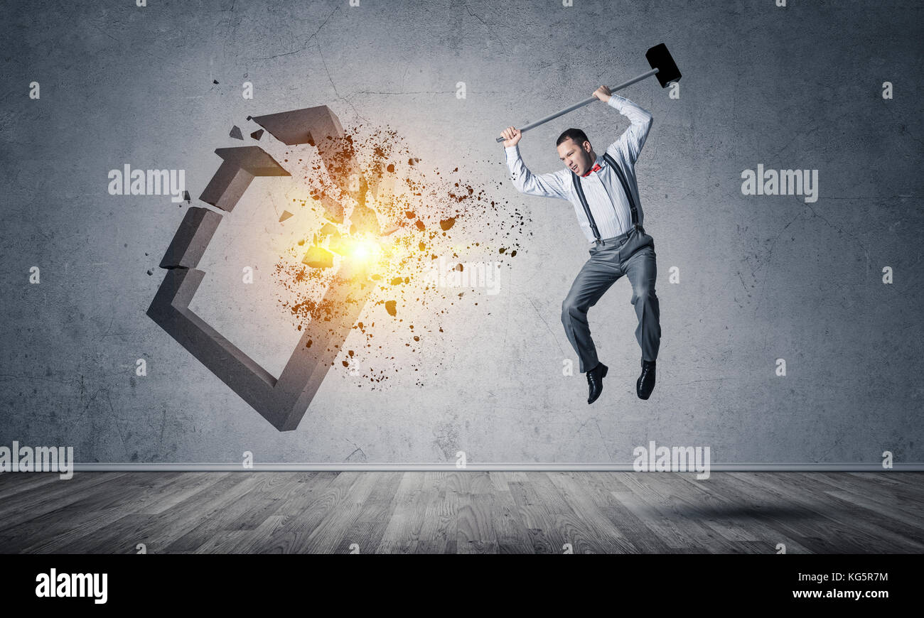 Determined businessman jumping and breaking with hammer house concrete ...