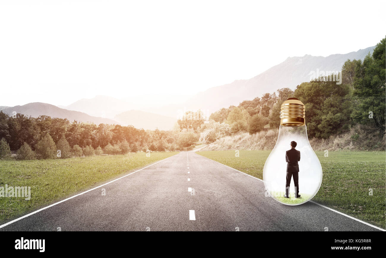 Young businessman trapped inside of light bulb on asphalt road Stock ...