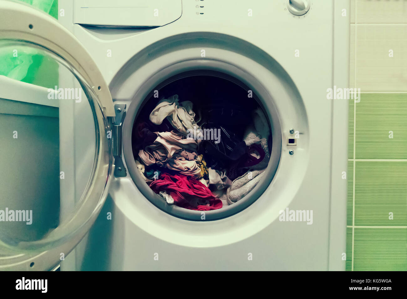 A close up of a washing machine loaded with clothes isolated on white ...