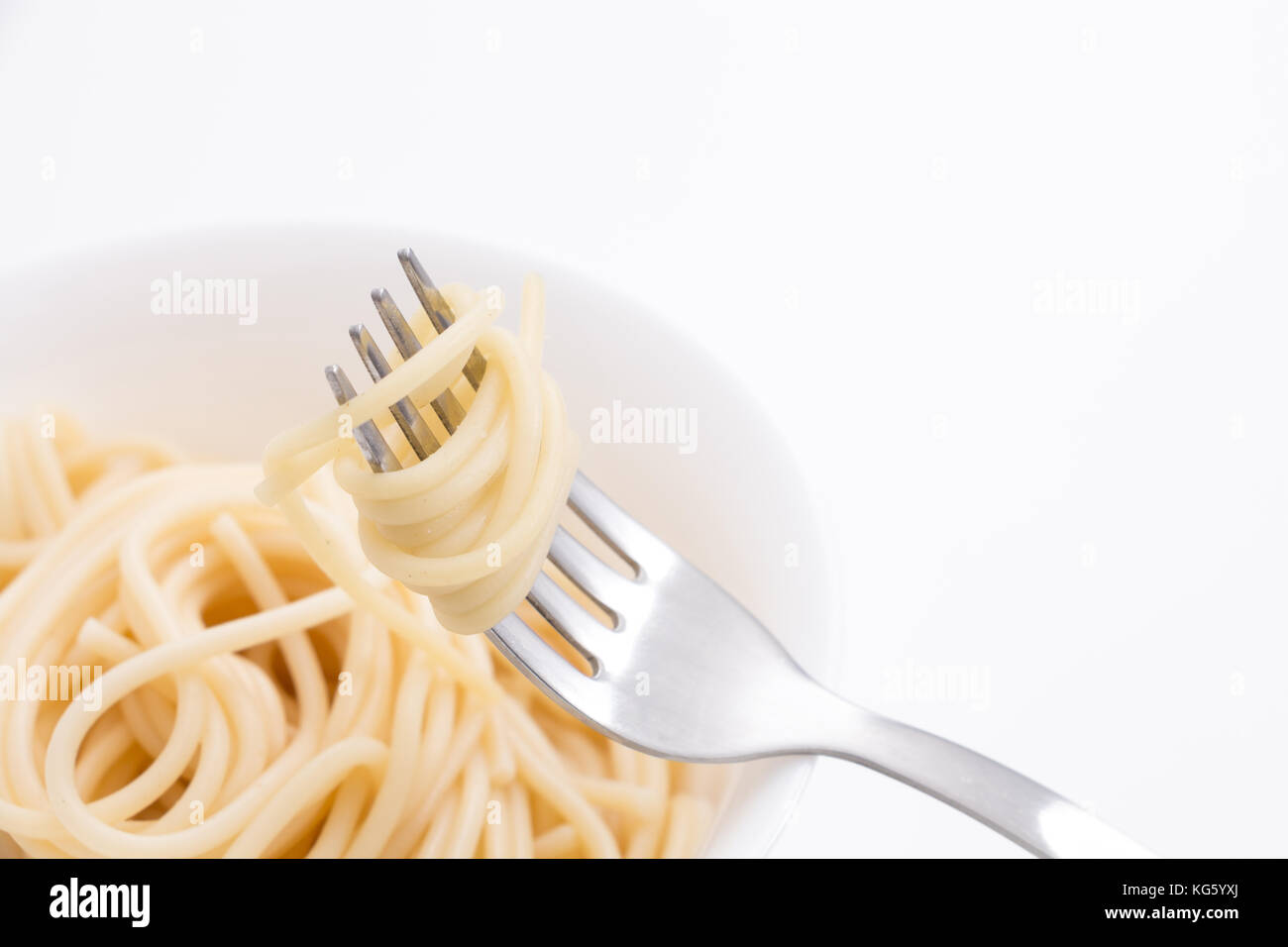 Plain cooked spaghetti pasta in white bowl and on fork, on white ...