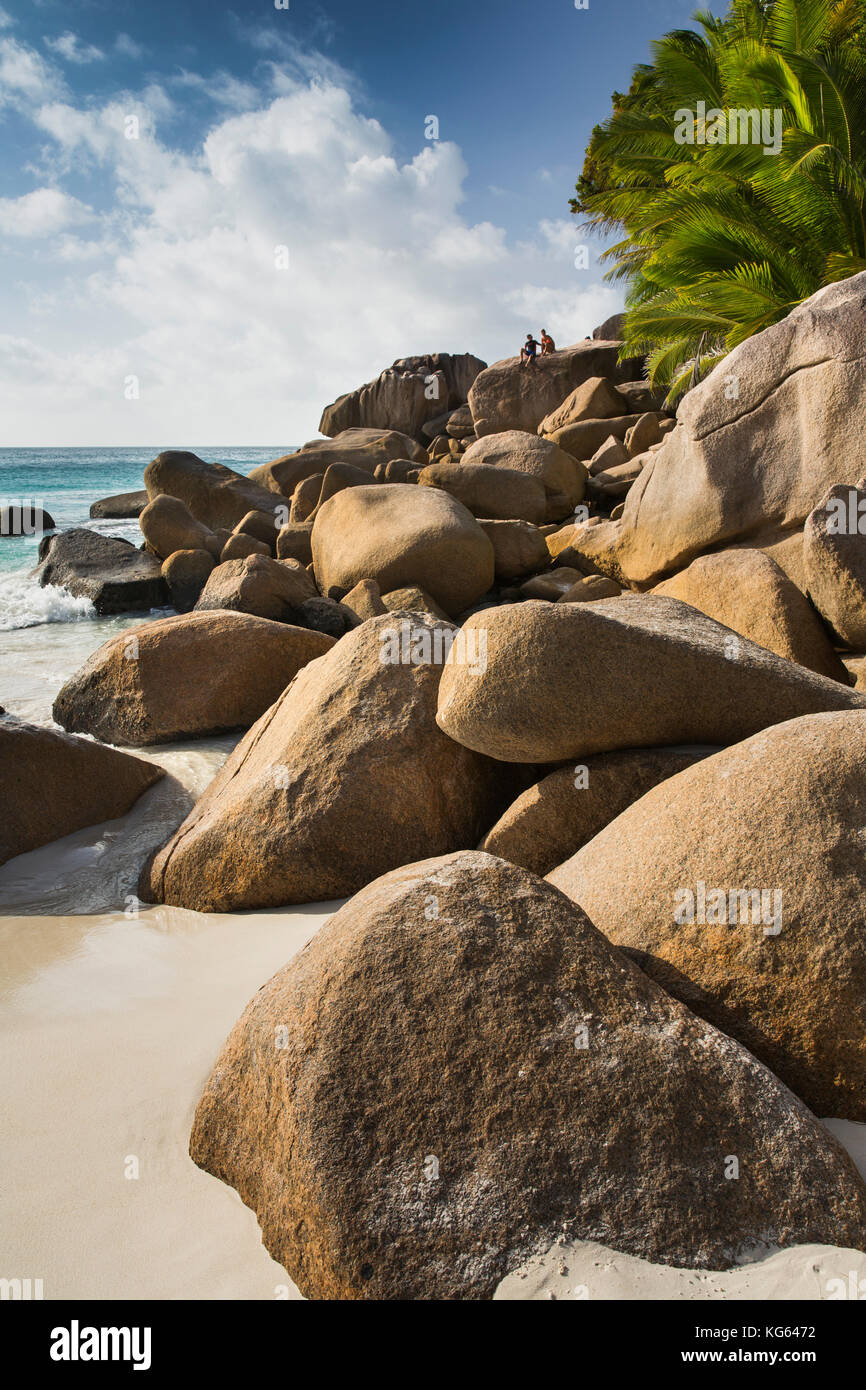 The Seychelles, Praslin, Anse Georgette, beach couple sat on rocks at ...