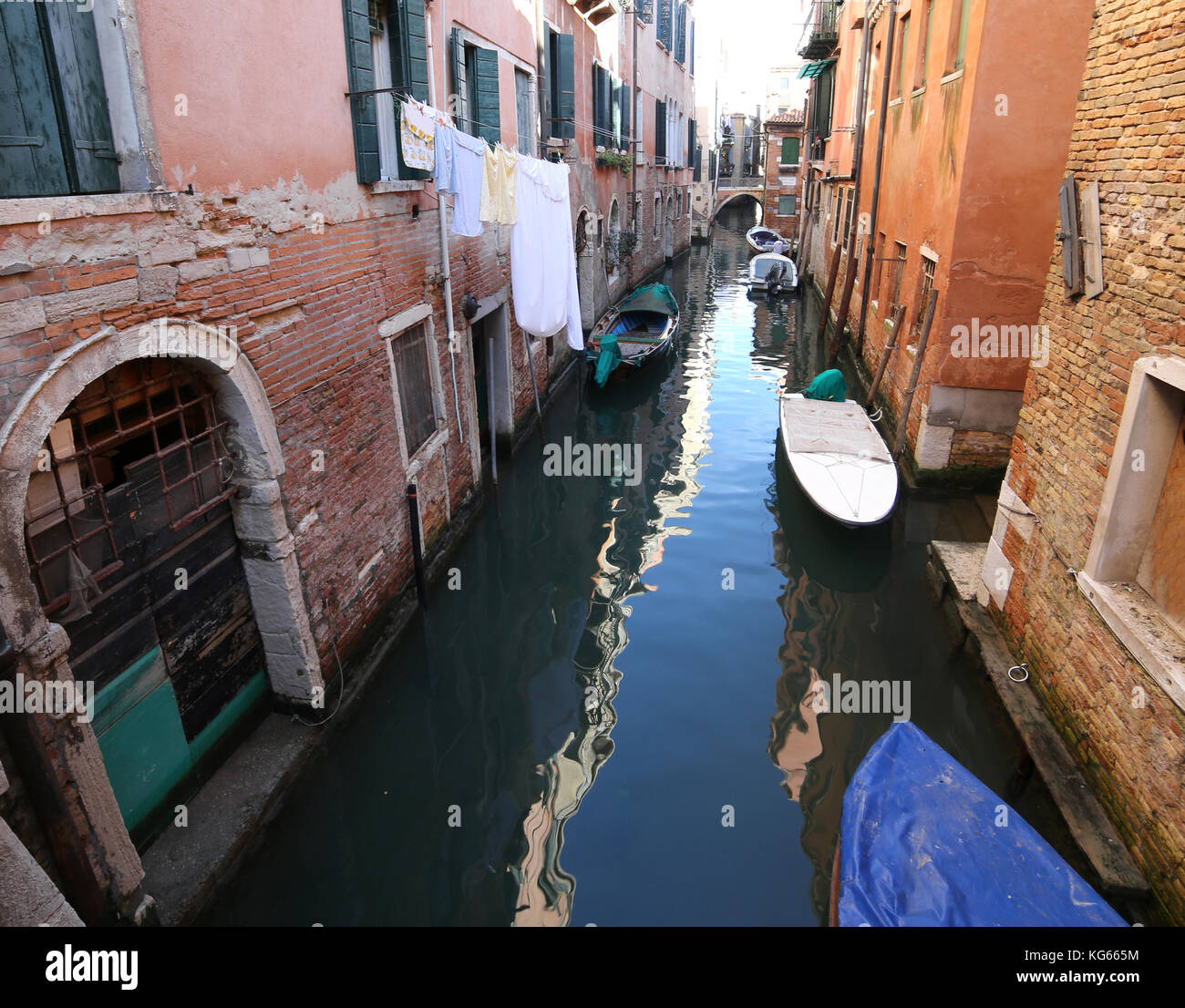 very narrow navigable canal in Venice in Italy with boats and italian ...