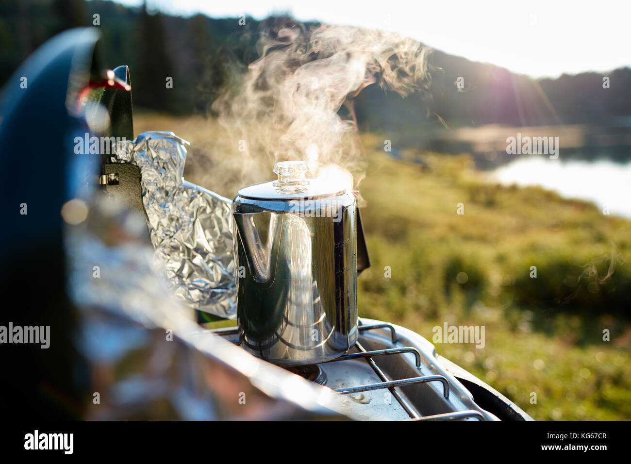 Boiling metal coffee pot on a gas burner with clouds of steam in early ...