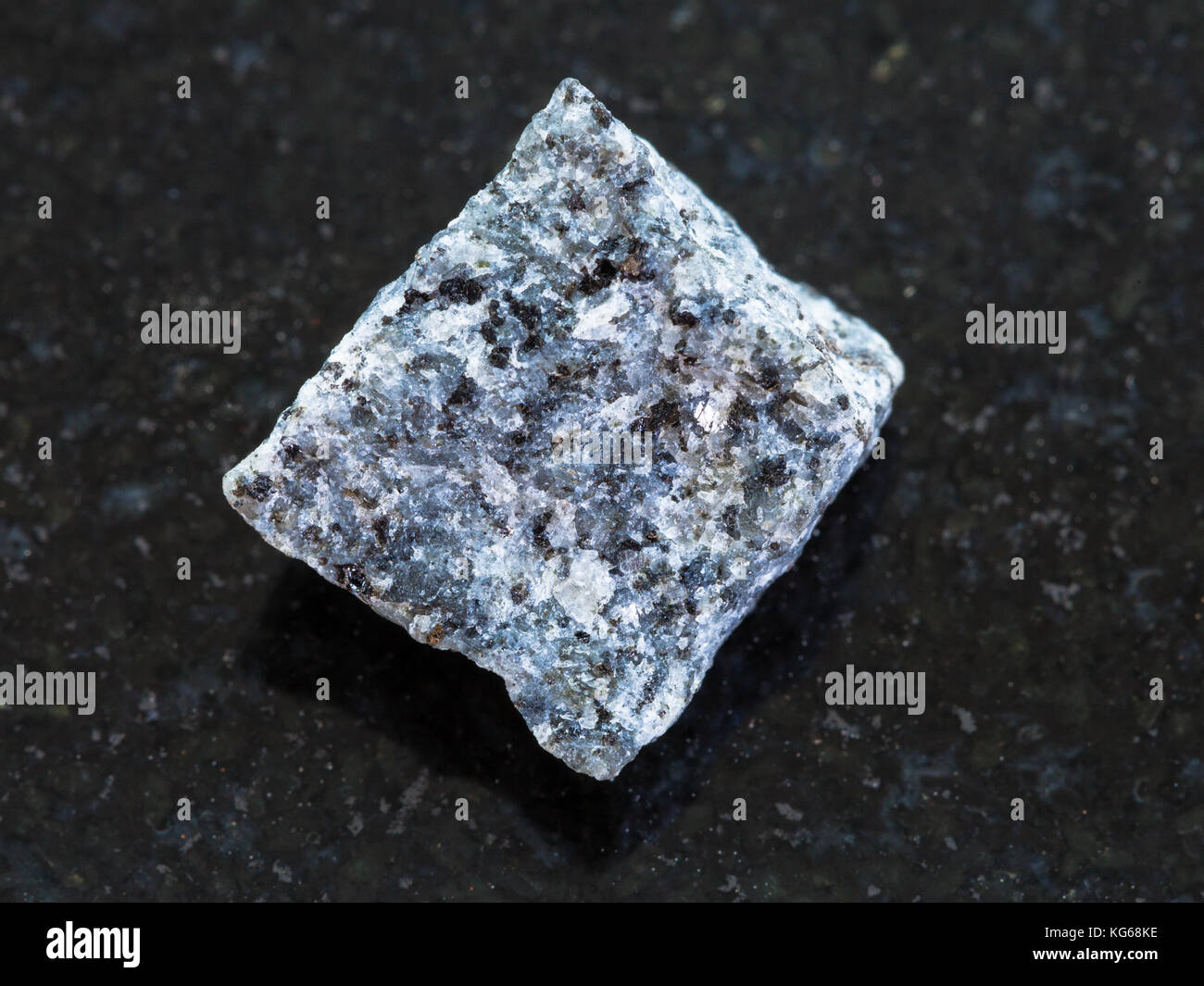 macro shooting of natural mineral rock specimen - rough Gabbro stone on dark granite background ...