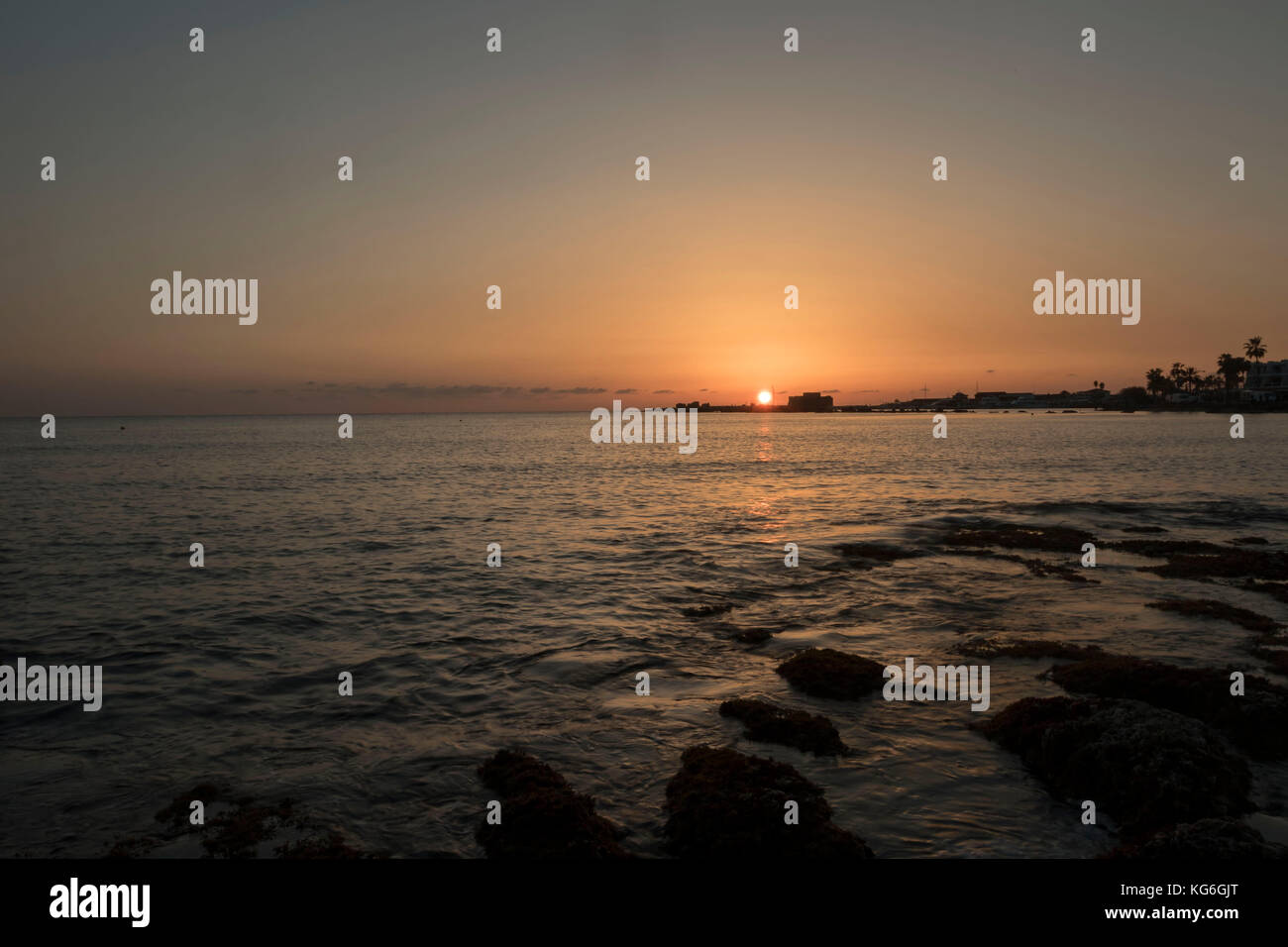 Sunset Paphos harbour with sea foreground Stock Photo - Alamy