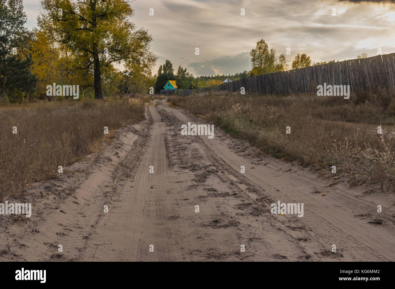 Landscape with sandy road leading to small green-yellow colored house ...
