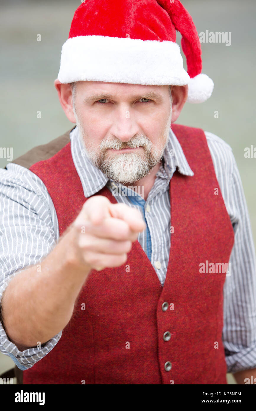 portrait of handsome man in his 50s with red Santa hat pointing with ...