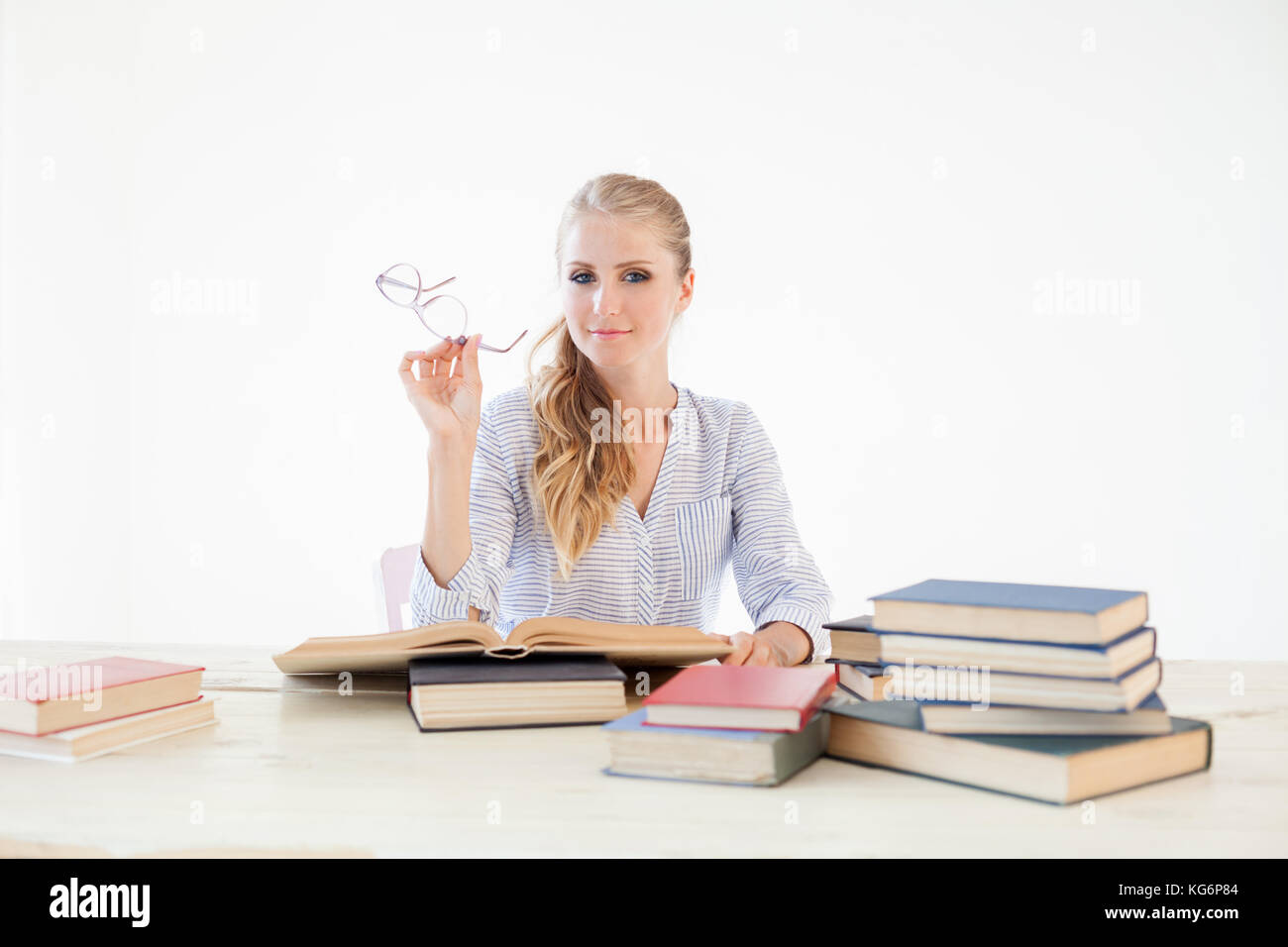 female teacher sitting at a table of many books Office Stock Photo - Alamy