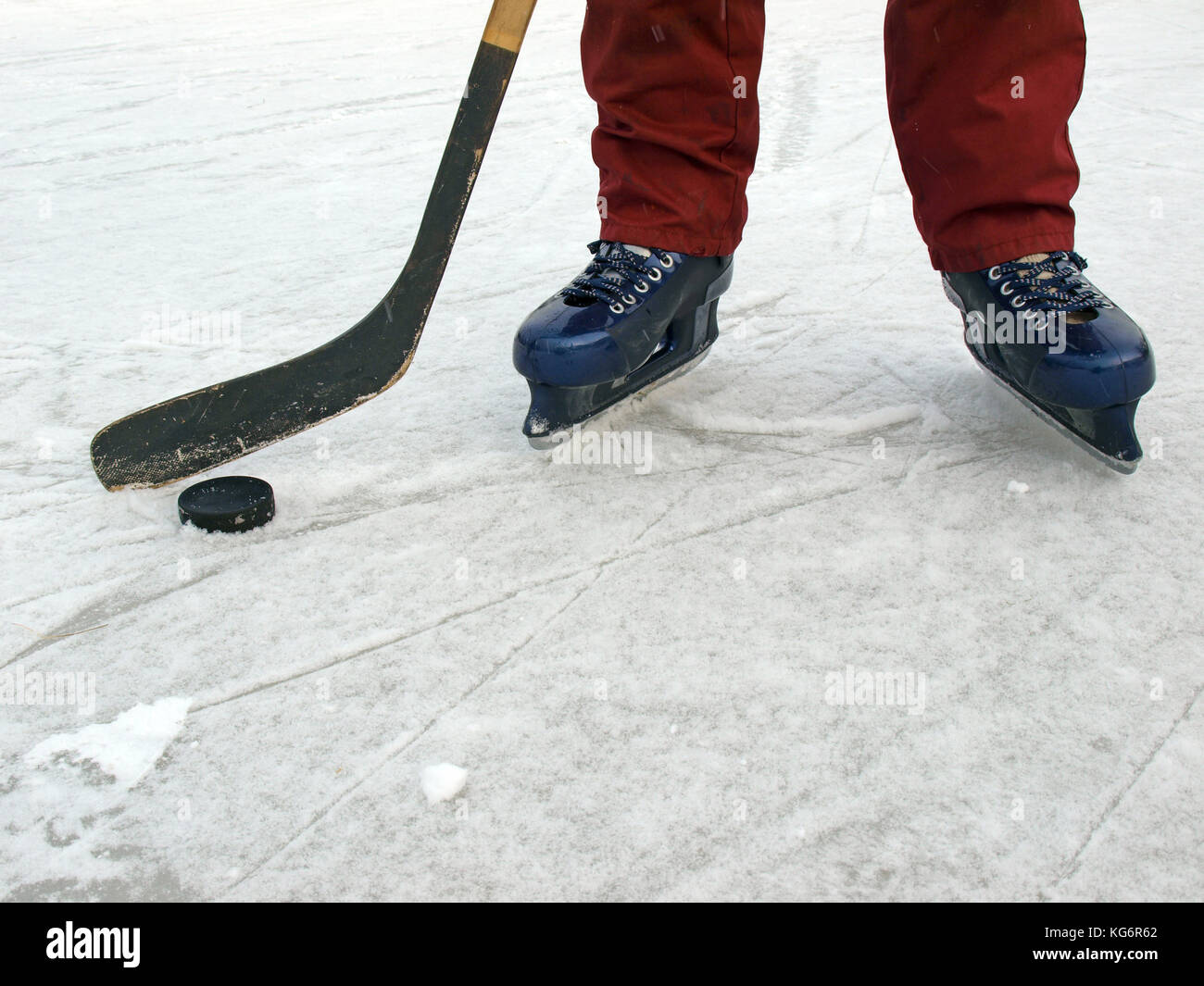 Ice hockey puck and kick and legs with skates Stock Photo - Alamy