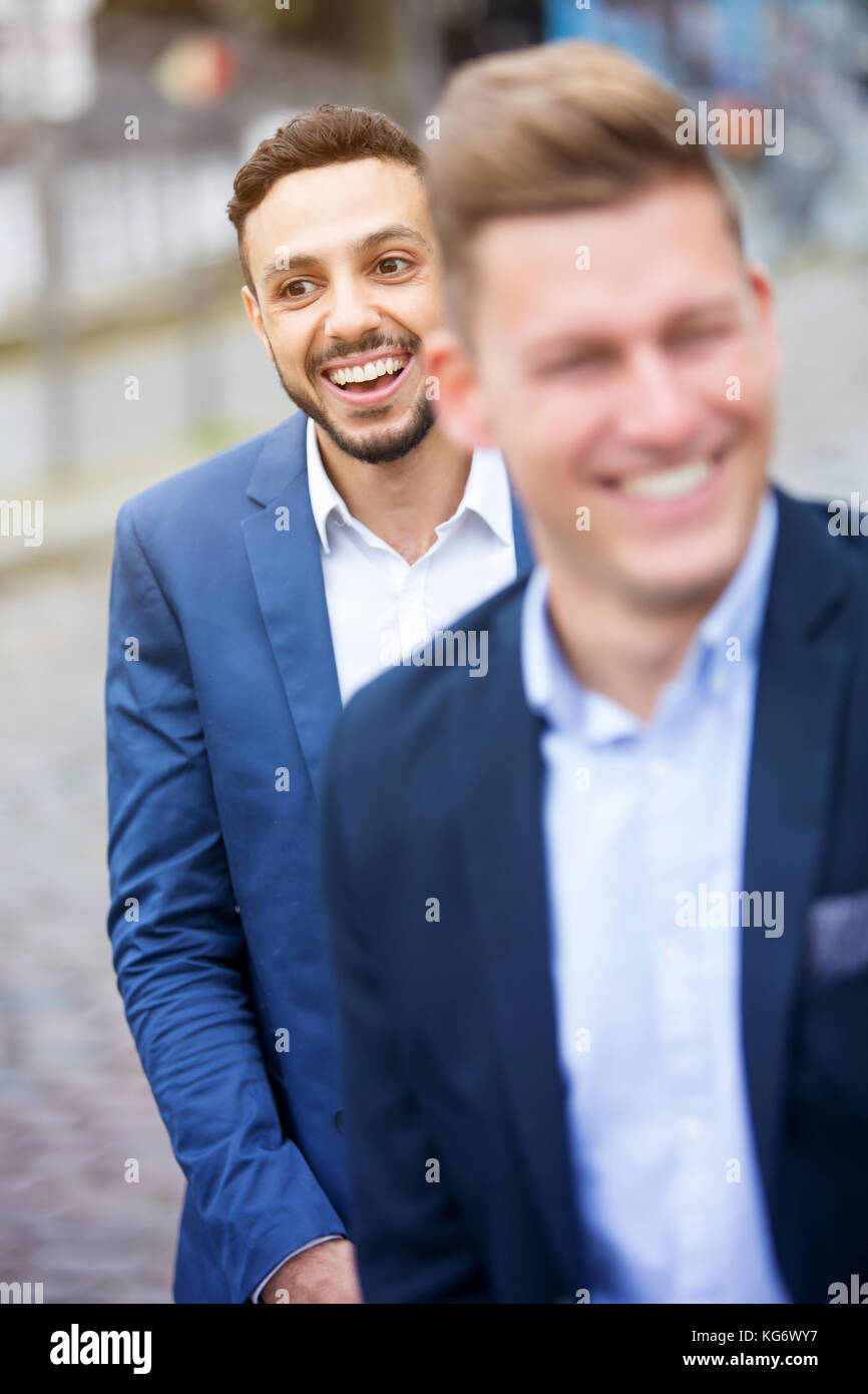two handsome businessmen standing outside and laughing Stock Photo - Alamy