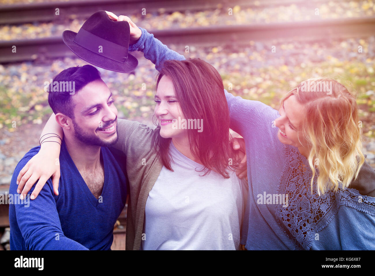 portrait of three friends sitting on train tracks and enjoying the sun ...