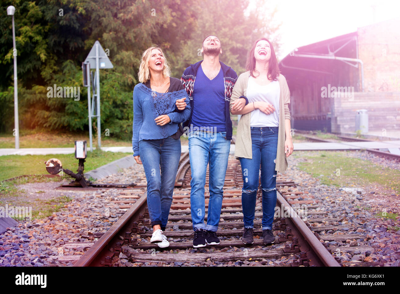 three friends walking on train tracks and having fun Stock Photo - Alamy