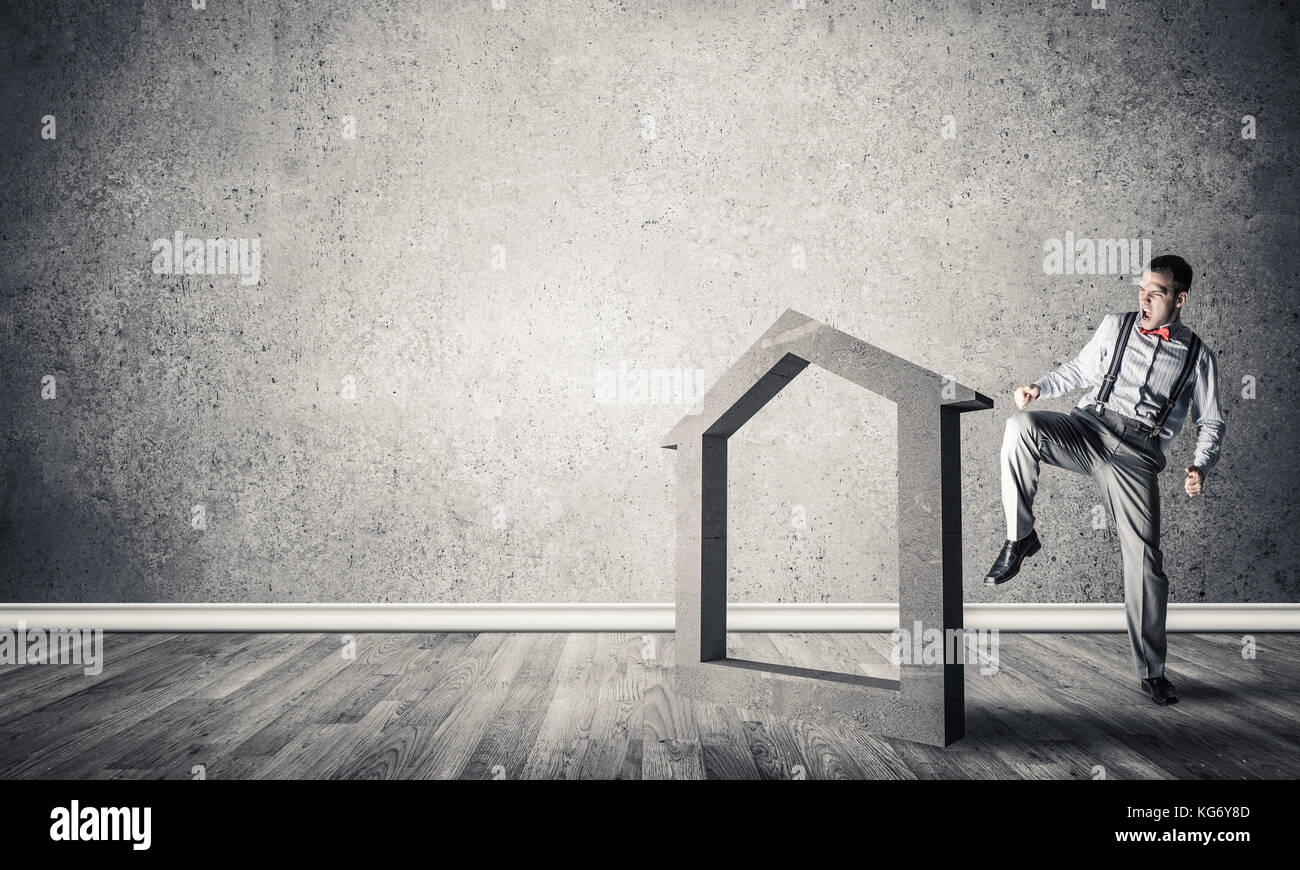 Determined businessman going to break with kick house concrete figure ...